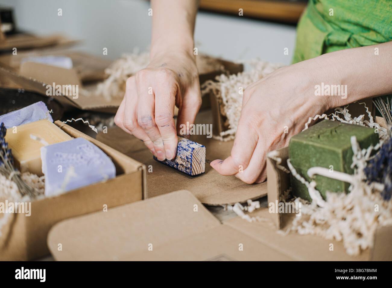 Person stamps a handmade soap bar with a logo inside kraft packaging ...