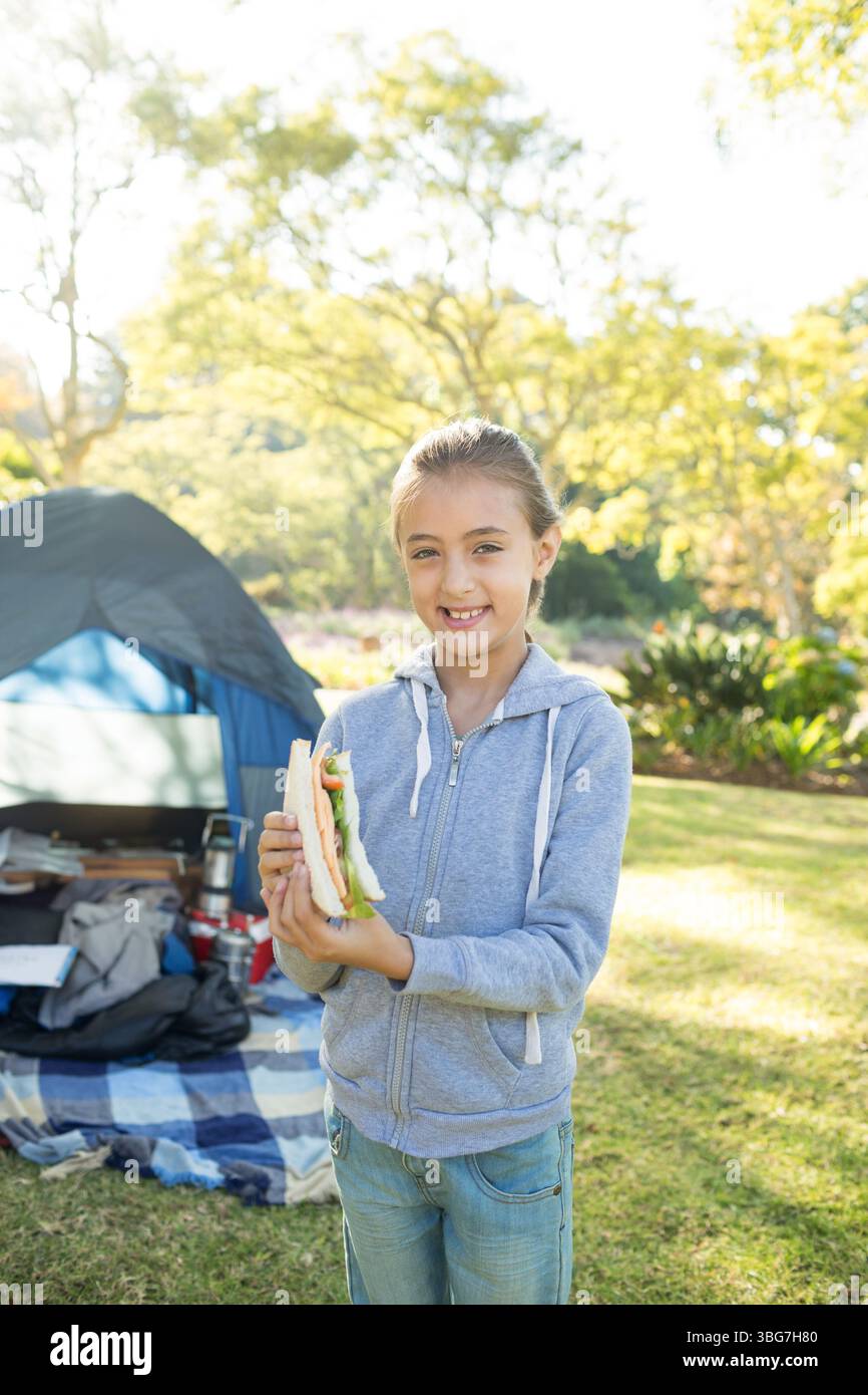 Sandwich and camping gear are sitting on blue checkered blanket beside ...