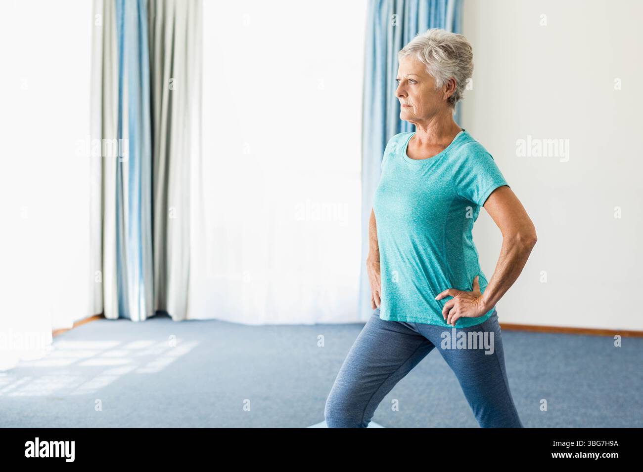 Senior woman wearing sportswear lunging forward in exercise room with ...