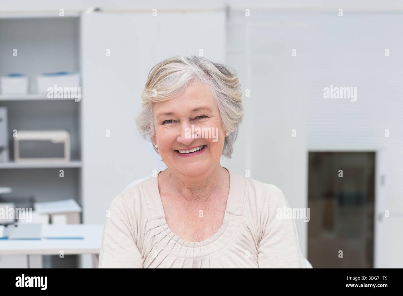 Smiling senior female sitting at desk in home office sorting paperwork ...