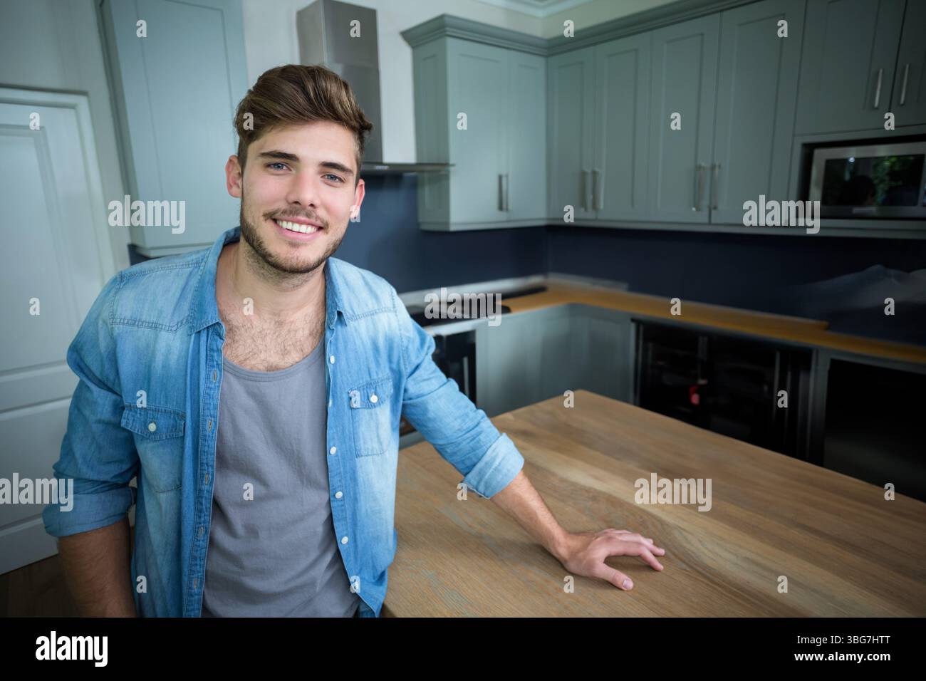 Man leaning on wooden kitchen island countertop in kitchen featuring ...