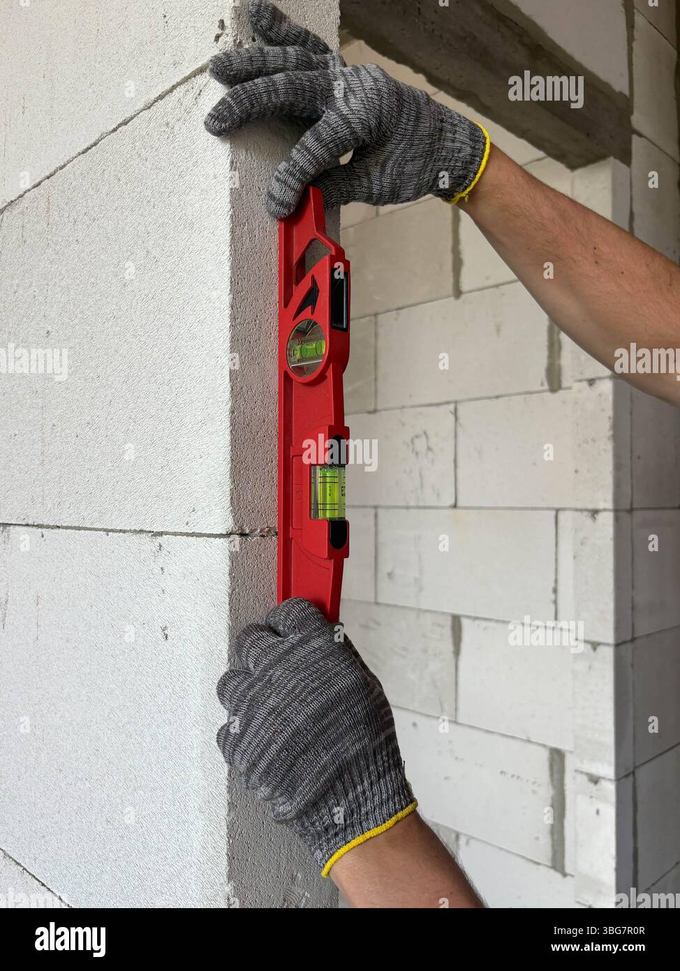 A close-up photo of a level in the hands of a builder measuring the ...
