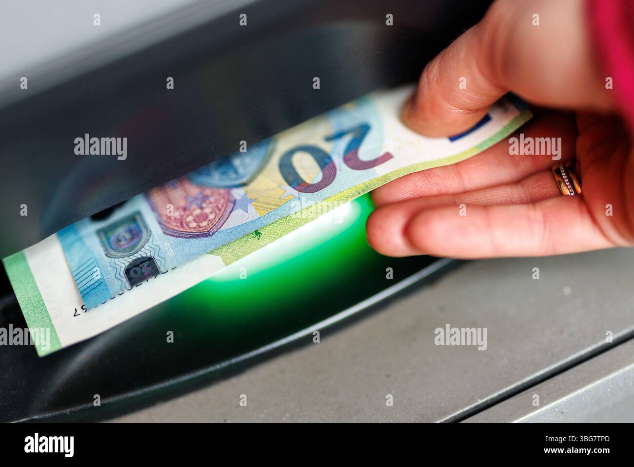 Munich, Germany. 29th May, 2025. A woman takes euro banknotes from an ...