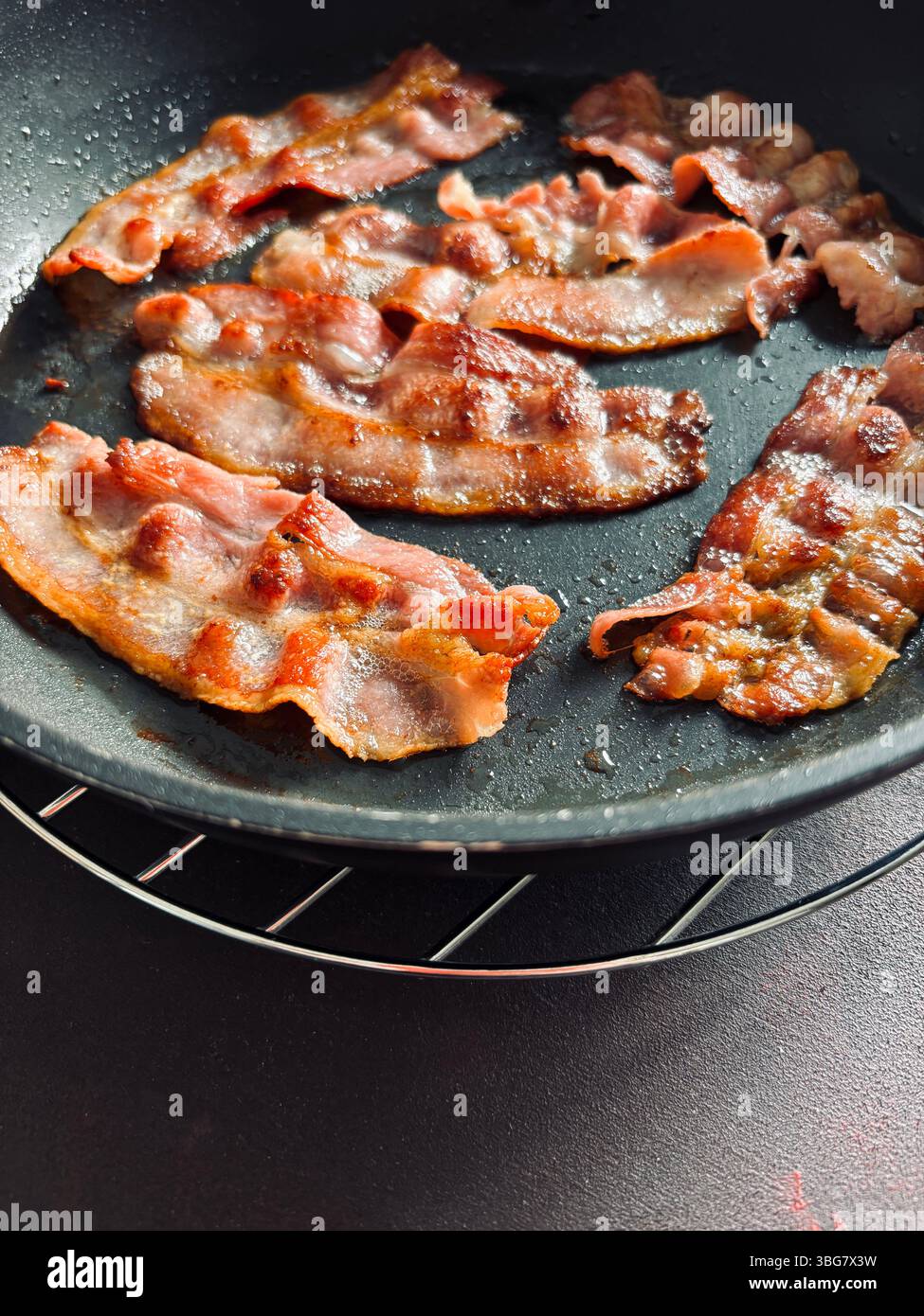 Slices fried bacon in a frying pan. Tasty fried bacon. Directly above ...