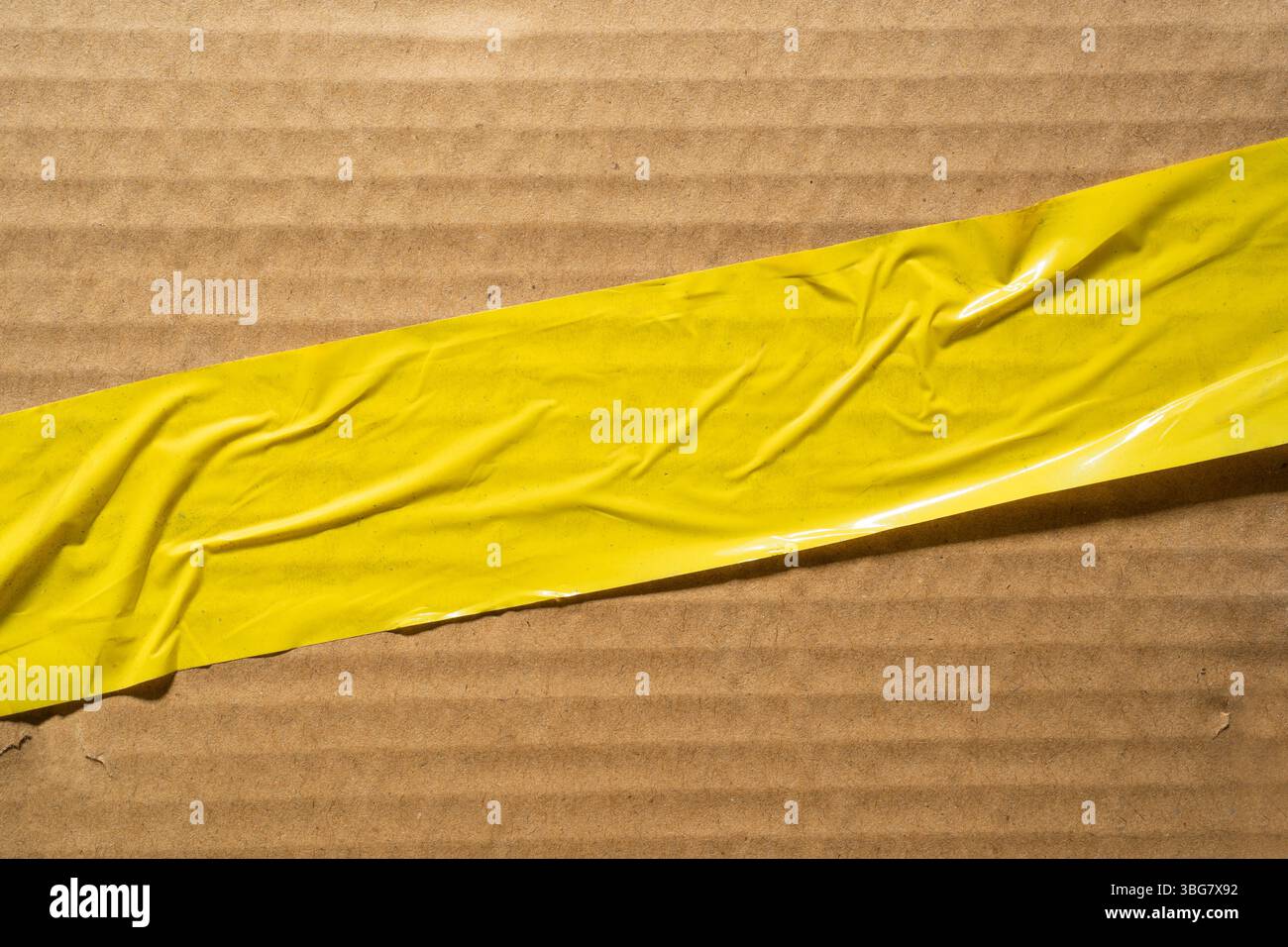Yellow parcel tape label on cardboard Stock Photo - Alamy