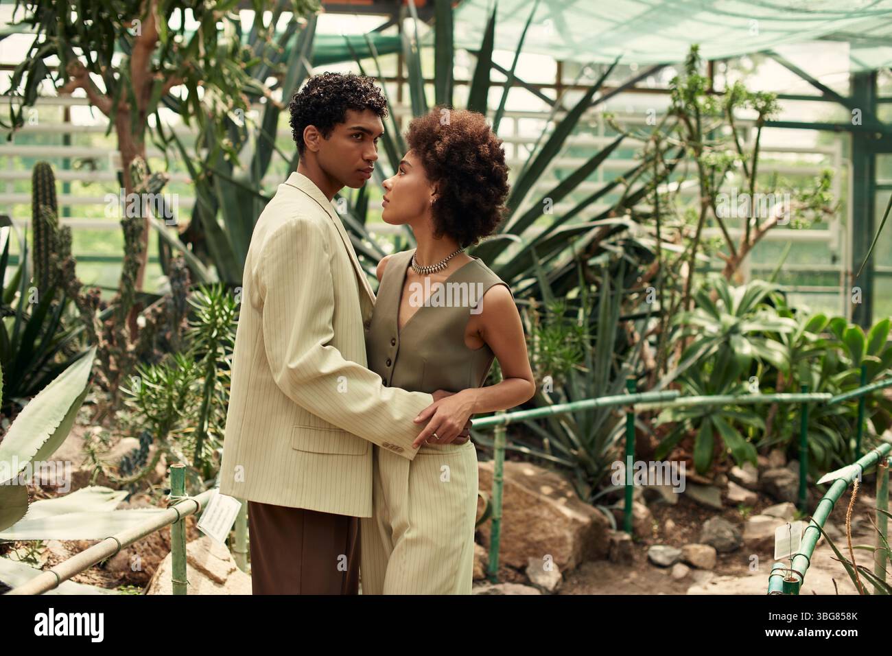 A couple embraces tenderly among diverse plants in a beautiful ...