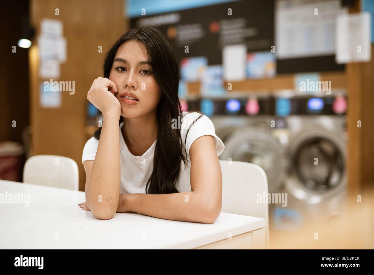 Young woman sitting in laundry shop doing housework Stock Photo - Alamy