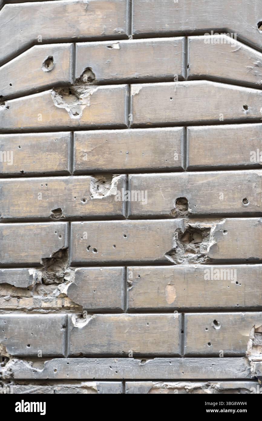 Close-up of damaged masonry with bullet and shell holes. The wall is ...