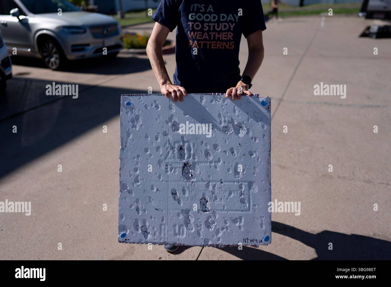 Hannah Vagasky holds a foam board hail pad covered with impact dents in ...