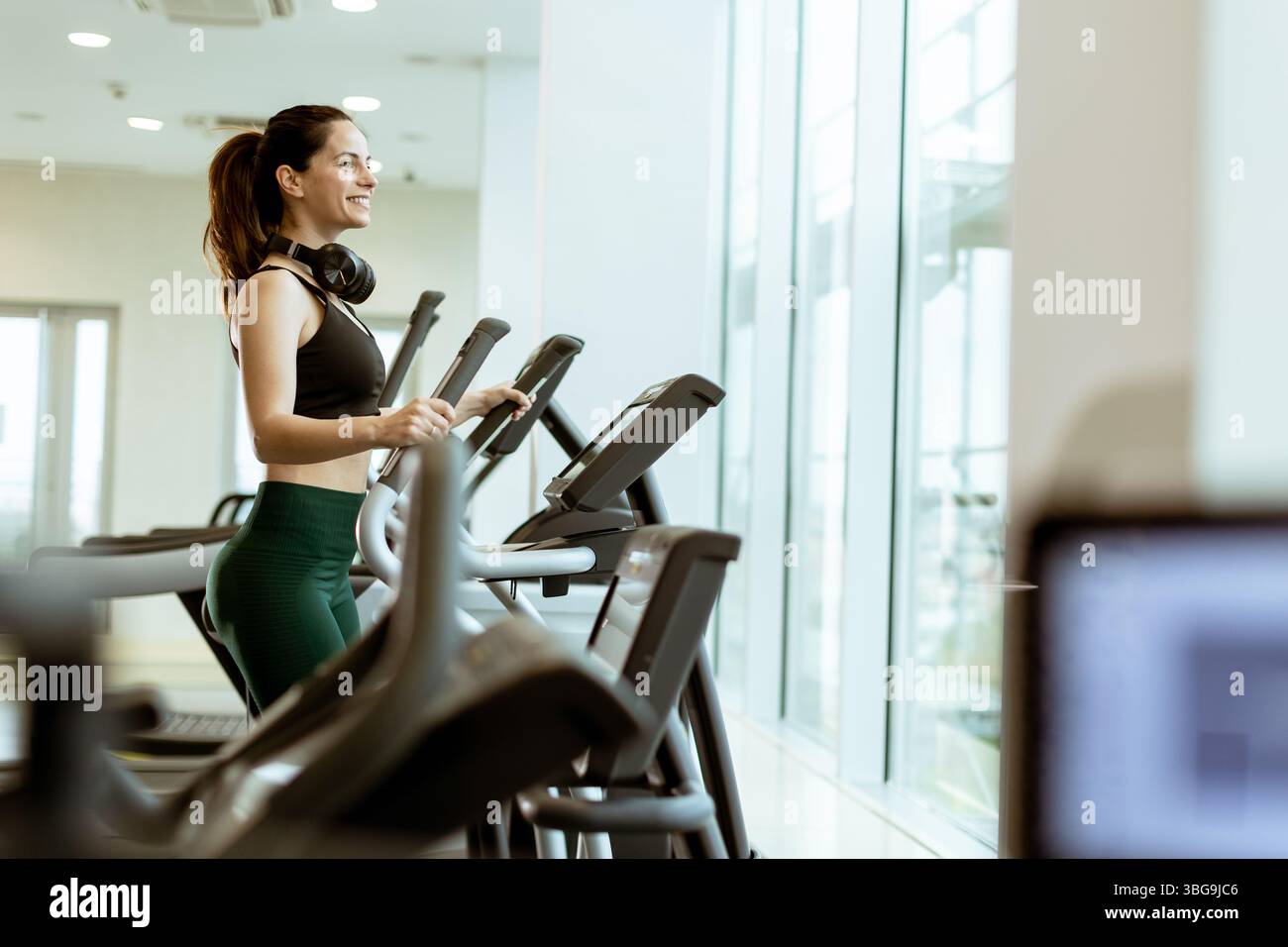 A dedicated woman engages in a cardio workout on an elliptical machine ...