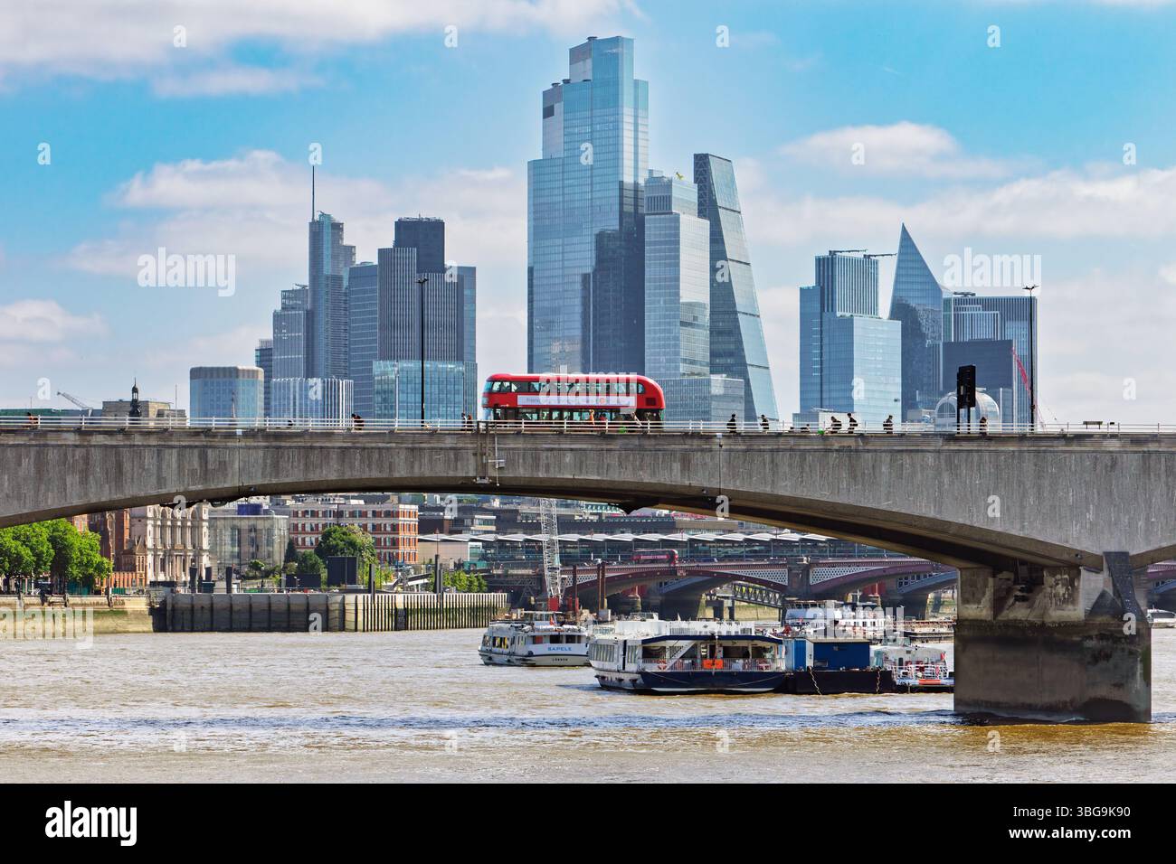 London skyline - a red bus crossing Waterloo Bridge with skyscrapers in ...