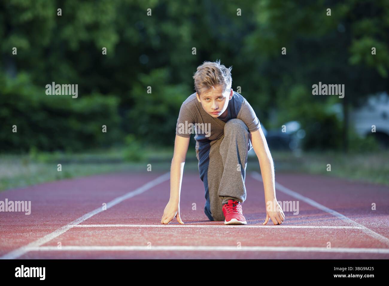 Low frontal full body view of a young male teenager in a low start ...