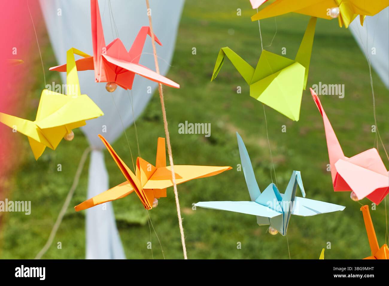 Bright origami cranes flutter in the wind in the field, creating an ...
