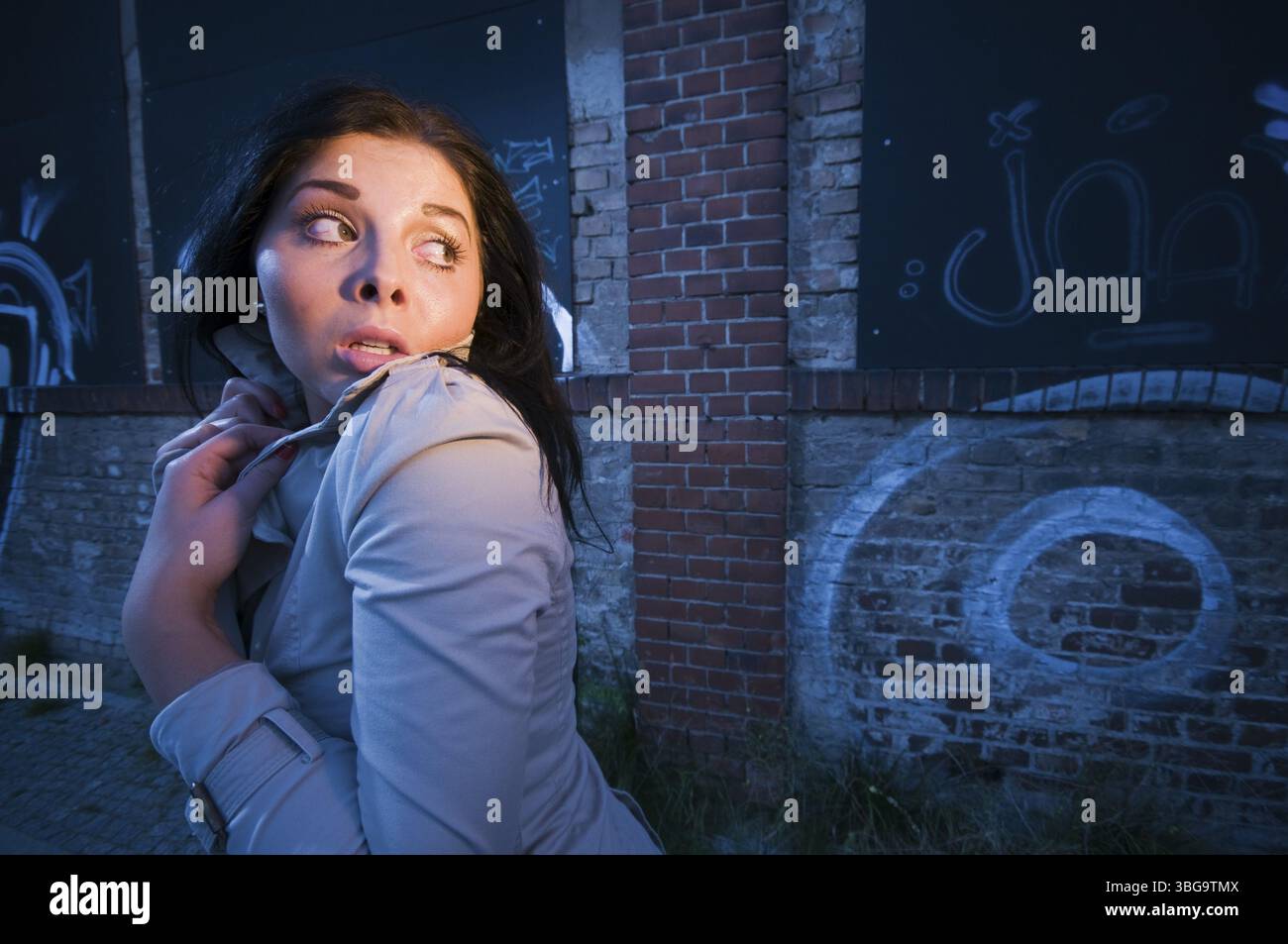 Young black haired woman on a brick wall sprayed with graffiti in the ...