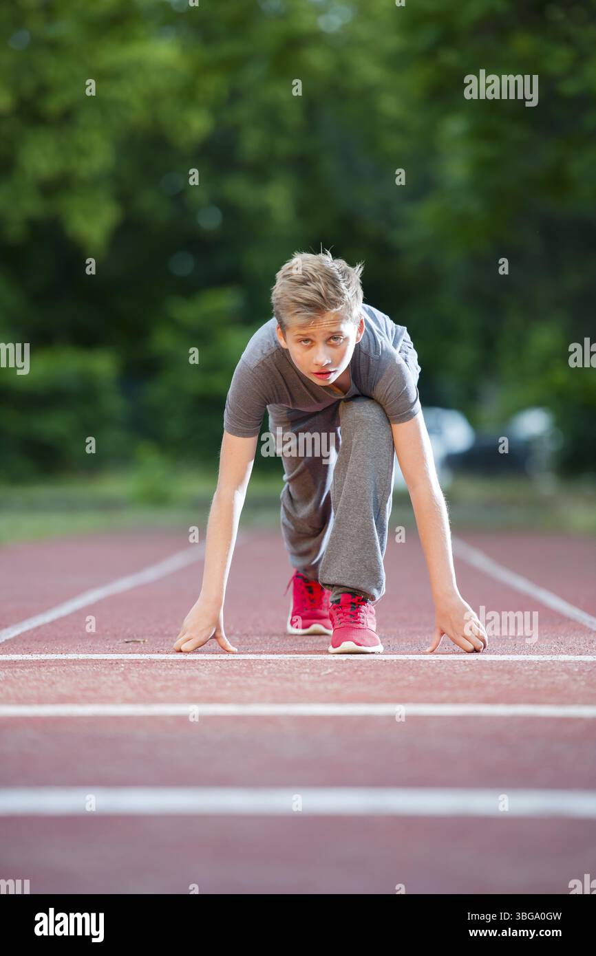 Low frontal full body view of a young male teenager in a low start ...