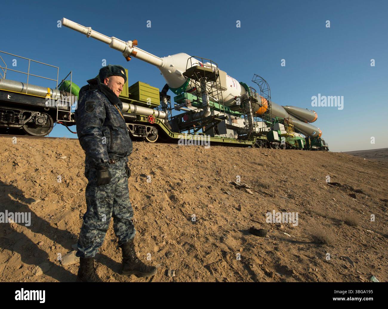 A security guard beside a Soyuz rocket as it is rolled out to the ...