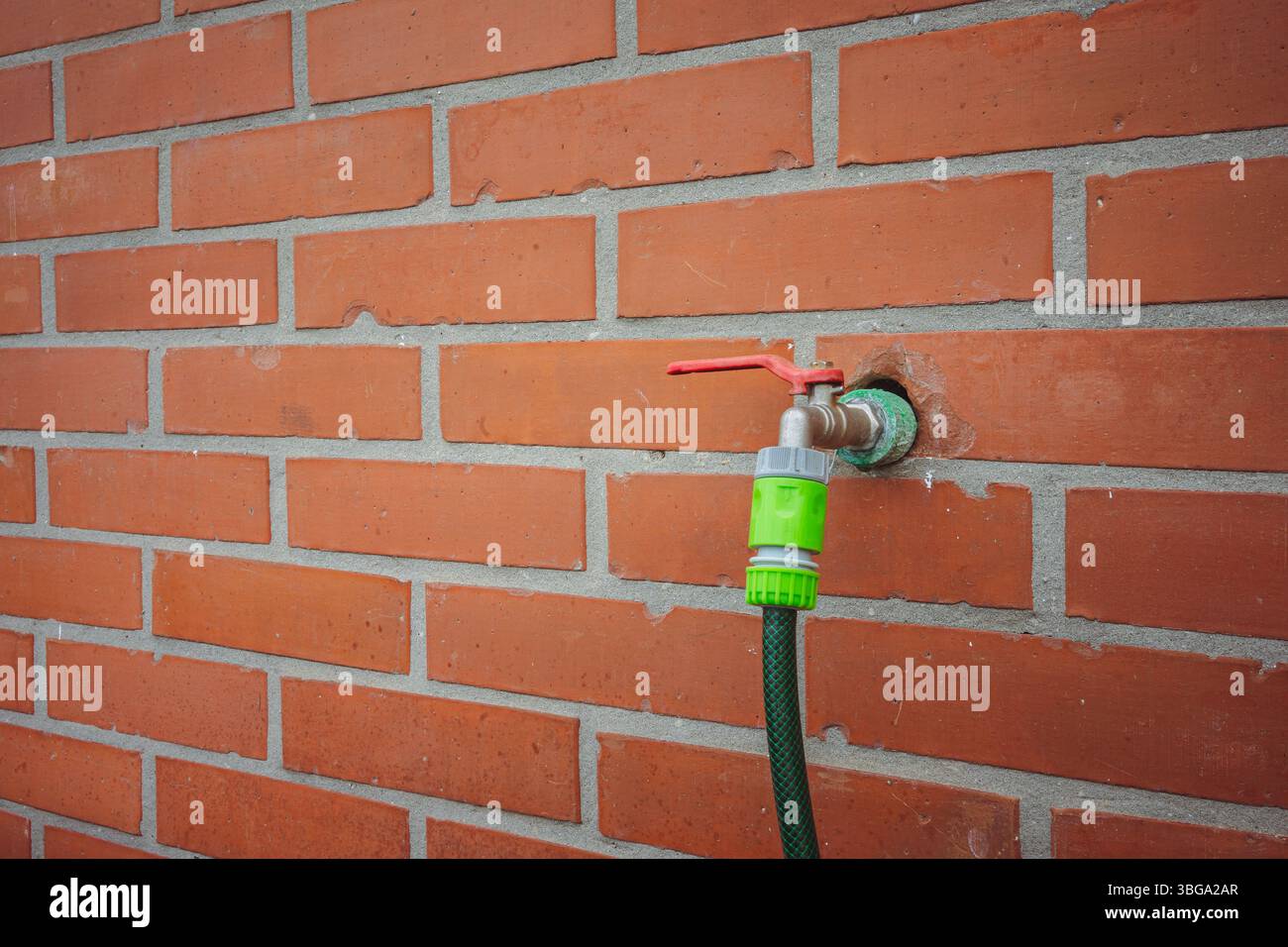 Fountain in classic brick wall with attached water hose Stock Photo - Alamy