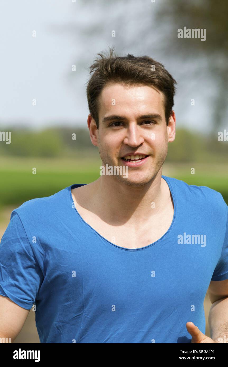 Frontal upper body shot of a young man in a blue T-shirt running on a ...