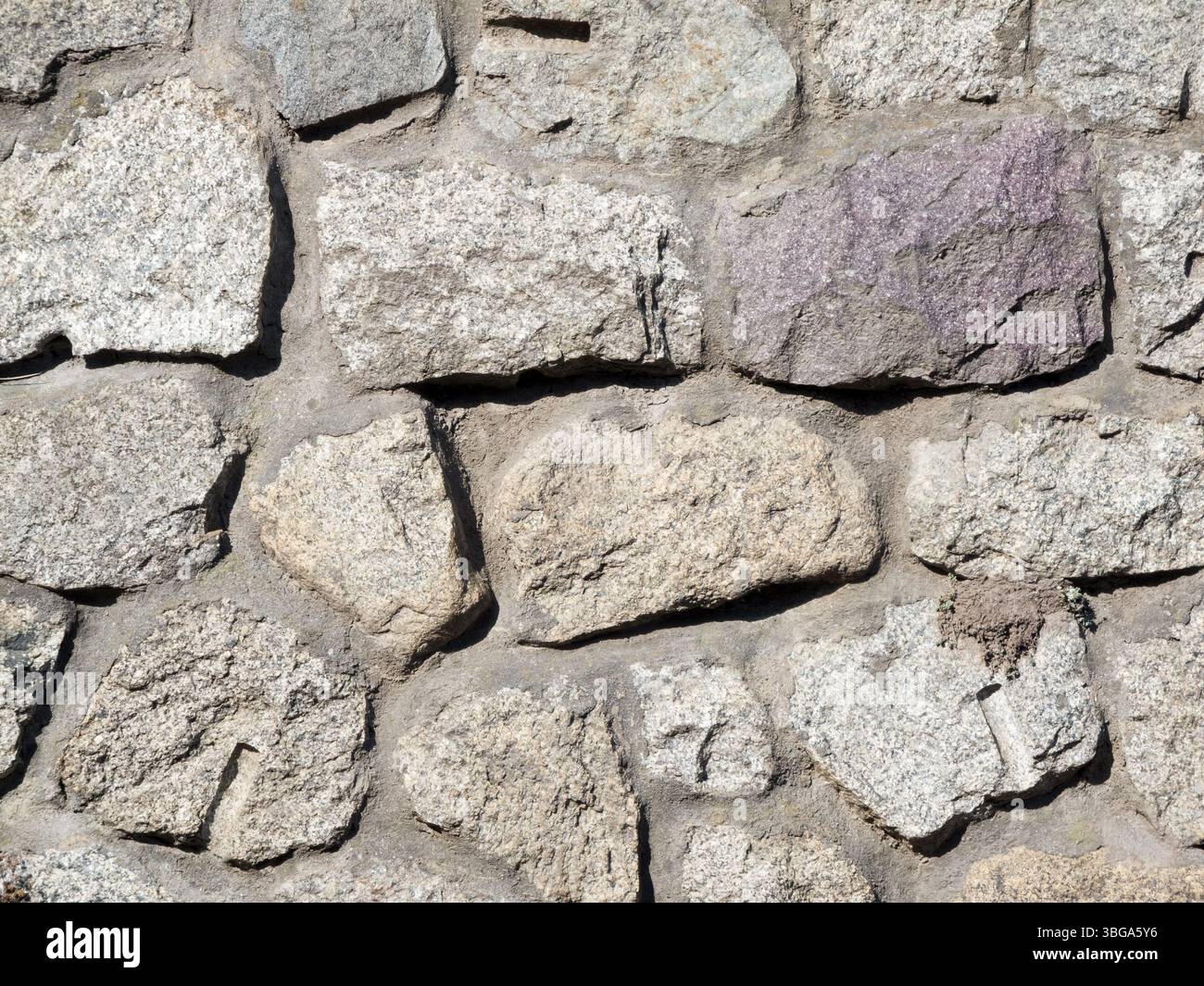 Full-format view of irregular granite stones as a masonry wall with ...