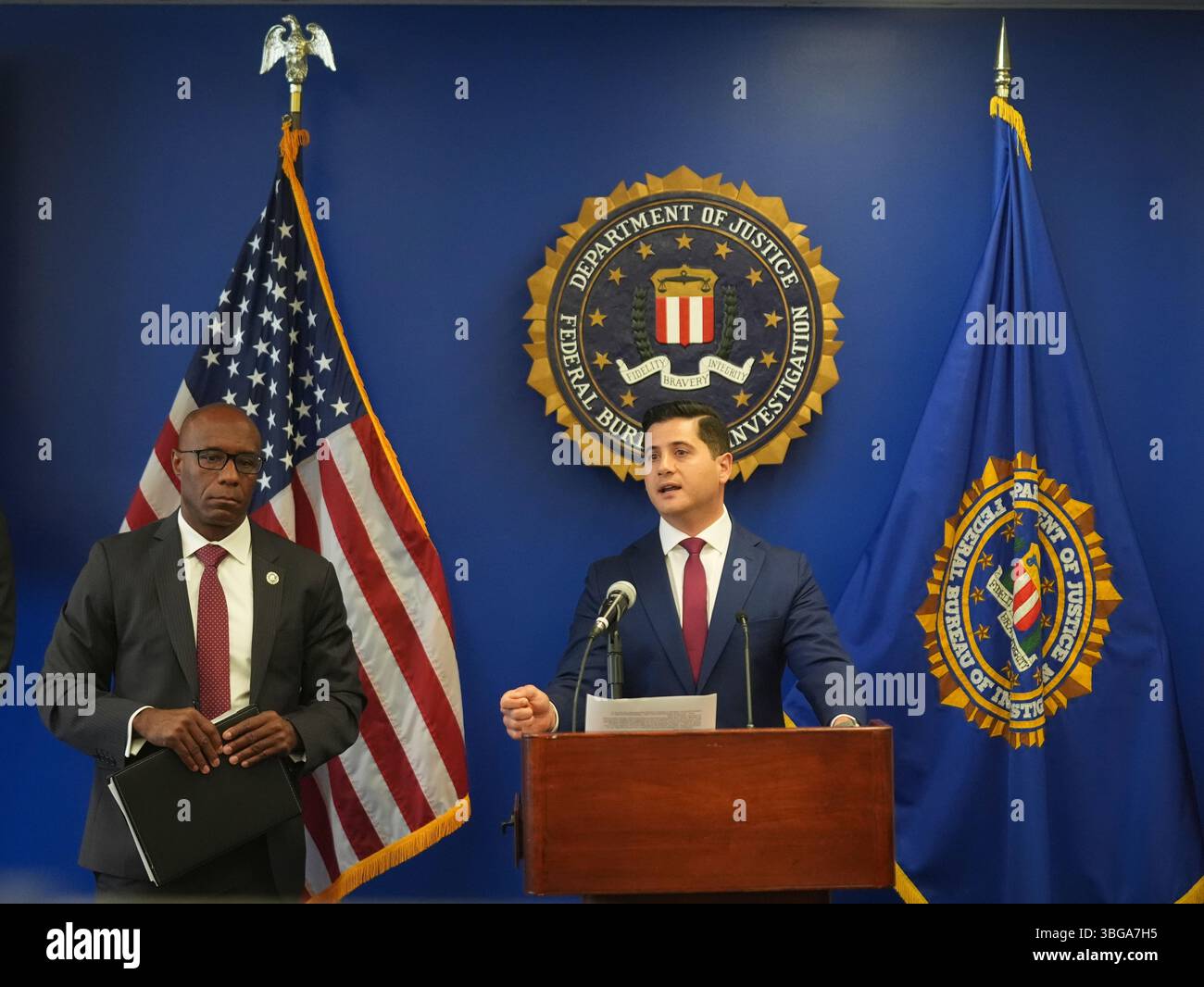 U.S. Attorney Bill Essayli, at podium with Akil Davis is the Assistant ...
