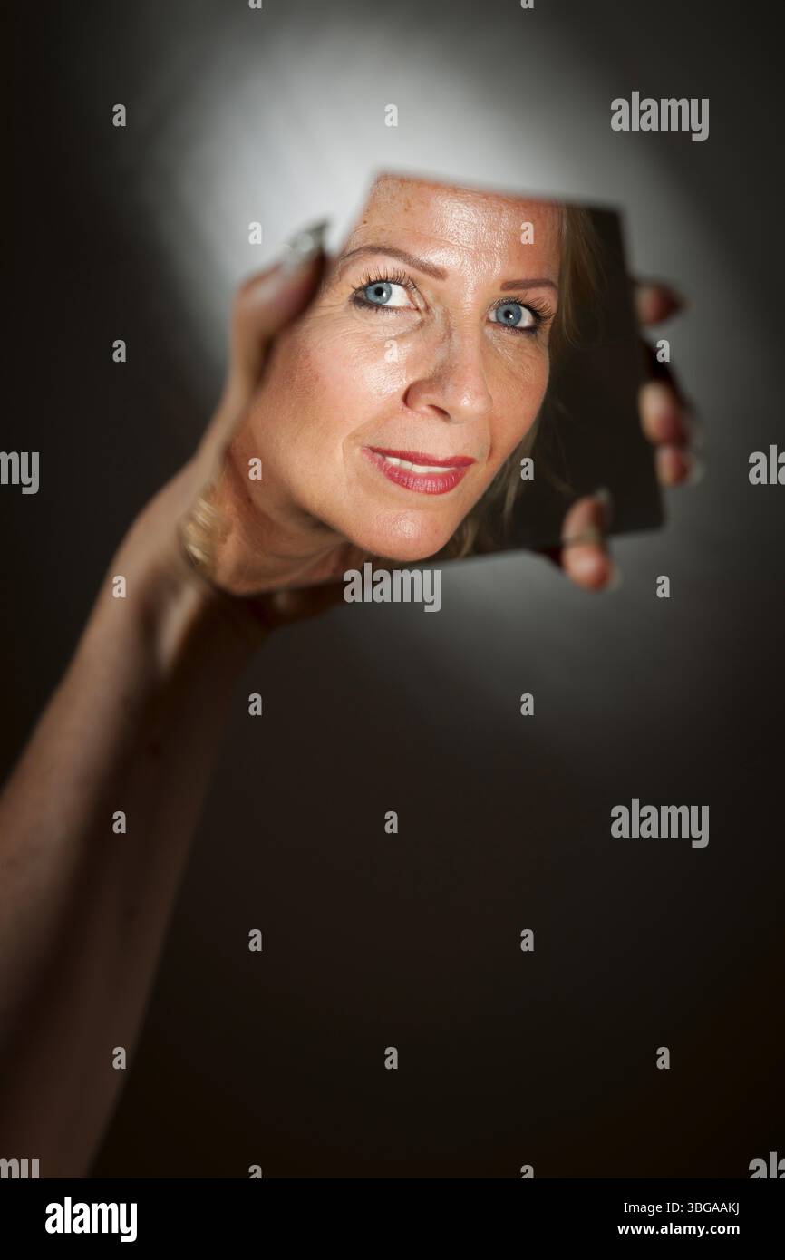 Mirror image of the face of a middle-aged blonde woman in a hand held ...
