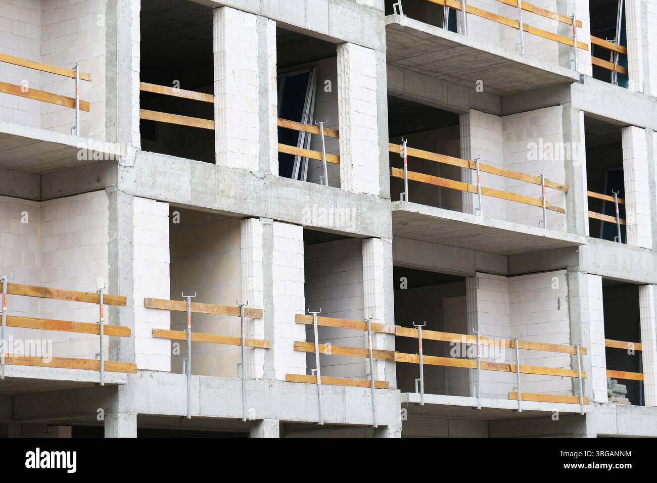 Concrete building under construction. Gray unfinished facade with windows. Modern residential ...