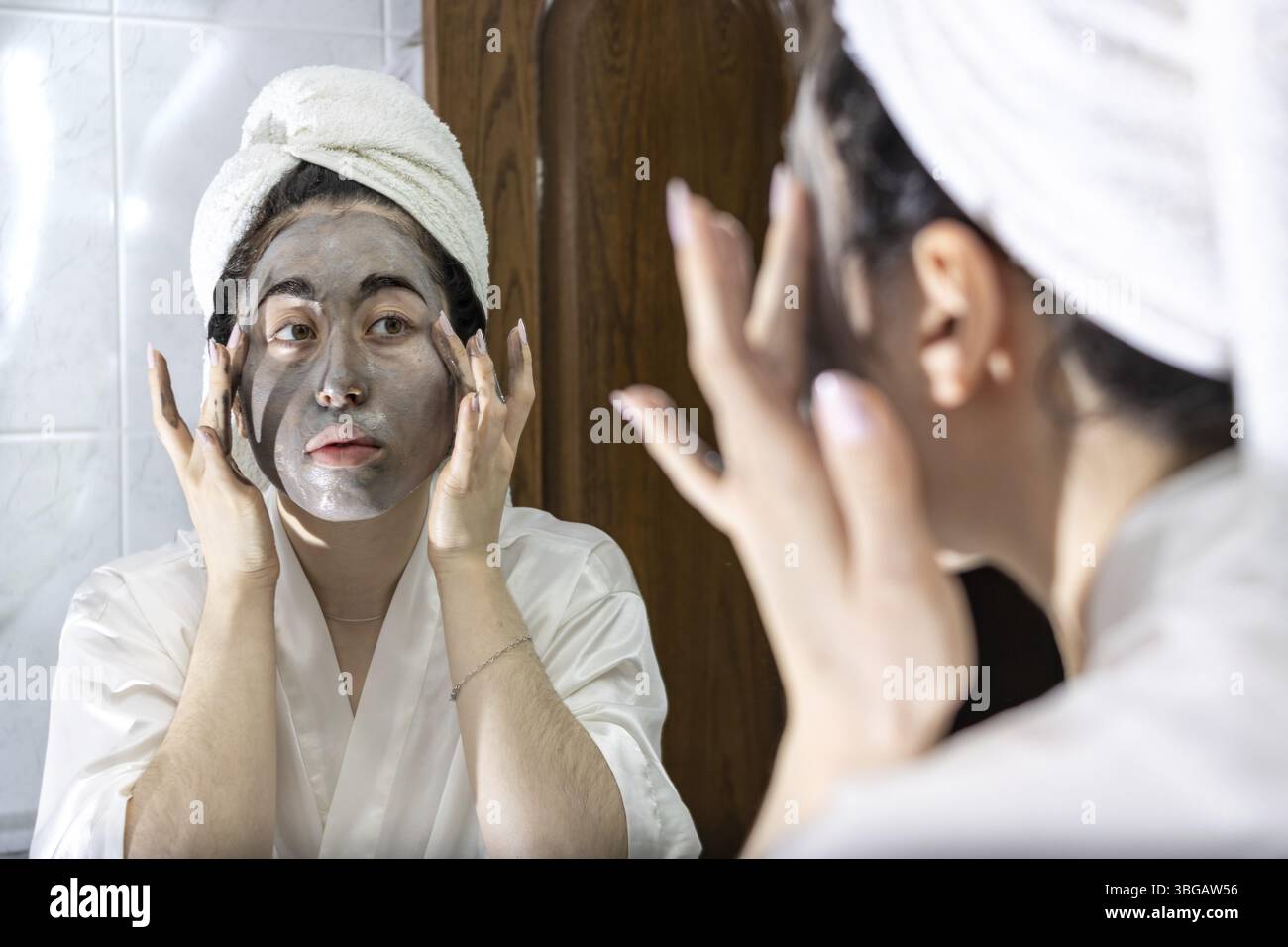 Portrait of a latin woman applying a facial mask after showering for a ...
