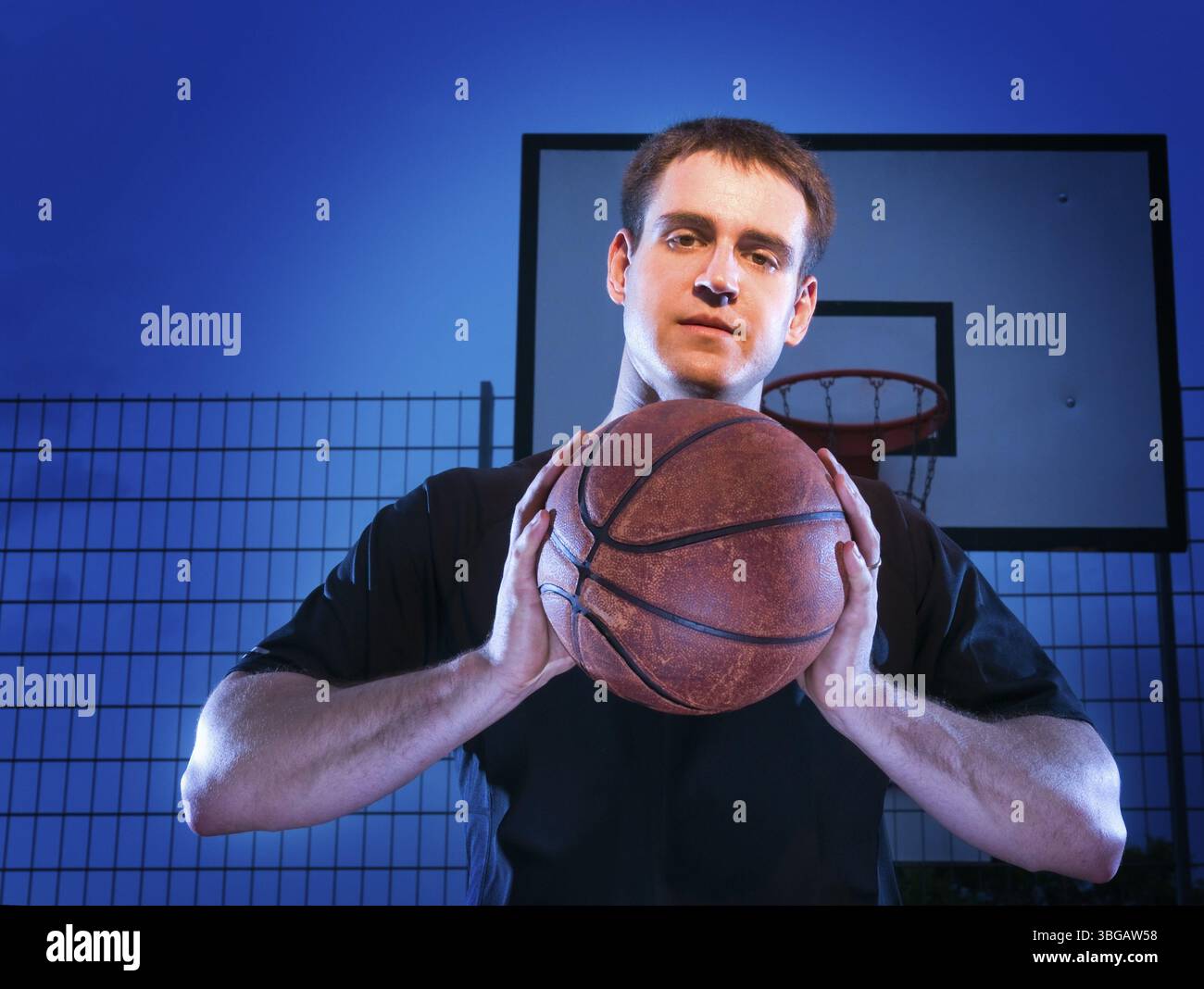 Frontal upper body view of a young man with a basketball in front of a ...