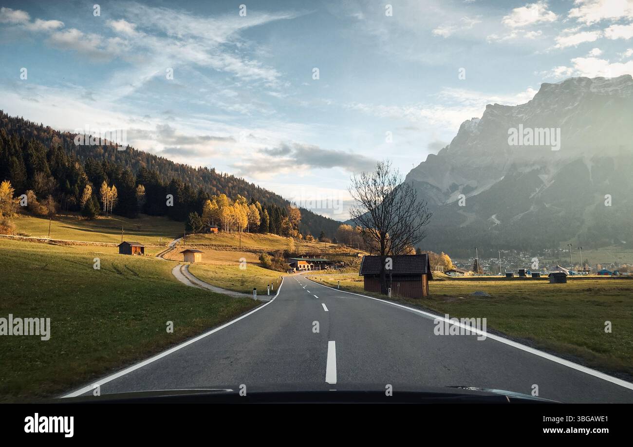 Empty road in mountain valley in rays of morning sun. Driving on curvy ...