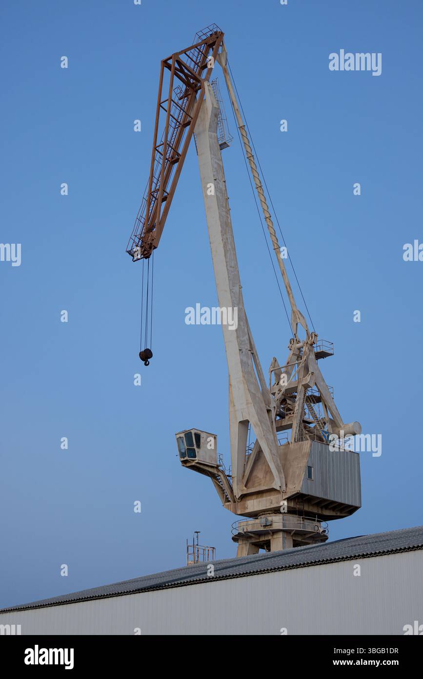 A large dockside industrial crane with a rusted boom and cabin ...