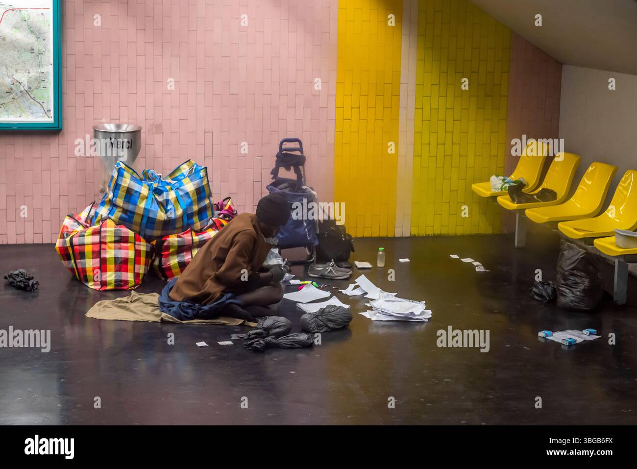 Homeless man doing his paperwork on a train platform, Paris, France ...