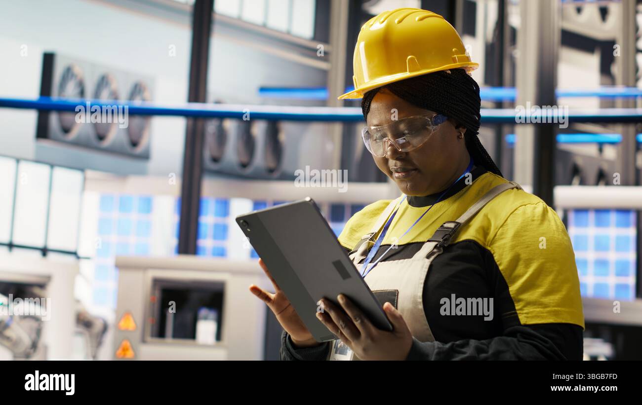 Smiling engineer in smart factory performing predictive maintenance using tablet, analyzing IoT ...