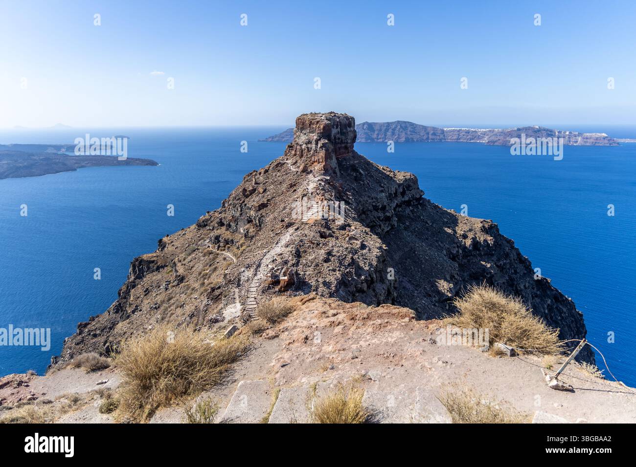 View through stone arch framing Skaros Rock trail and ruins with hikers ...