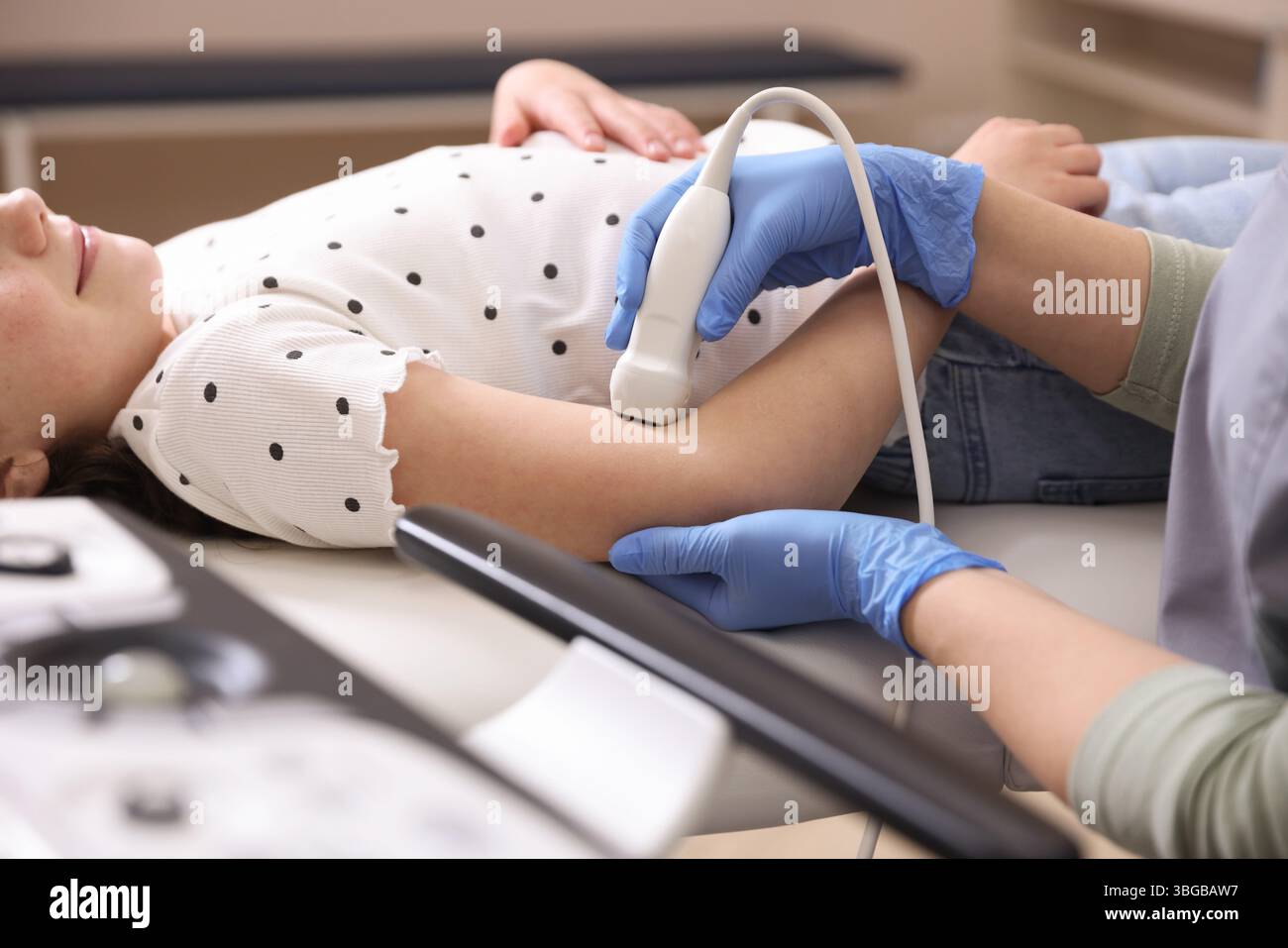 Sonographer conducting ultrasound examination of girl's arm in clinic ...