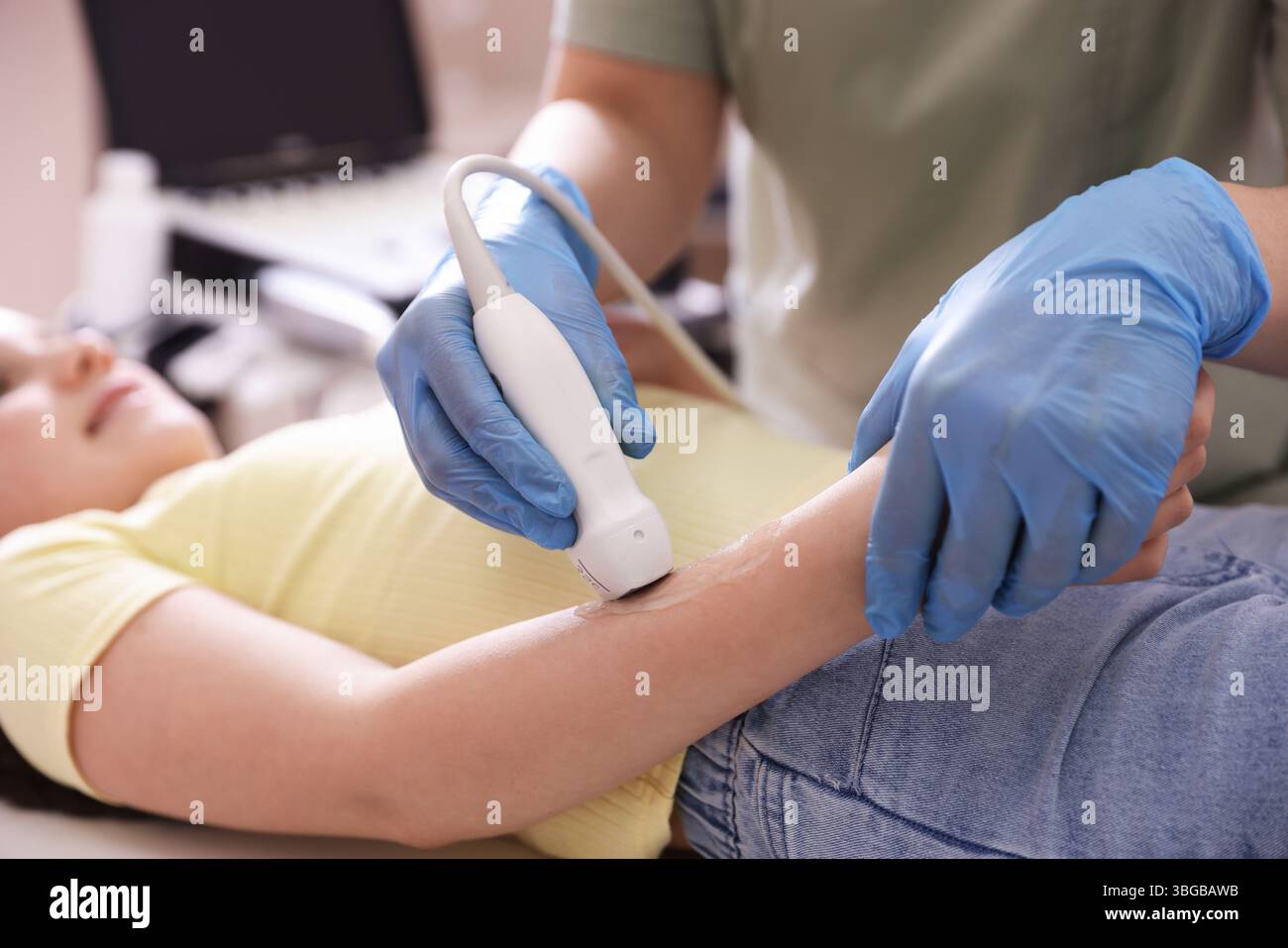 Sonographer conducting ultrasound examination of girl's arm in clinic ...
