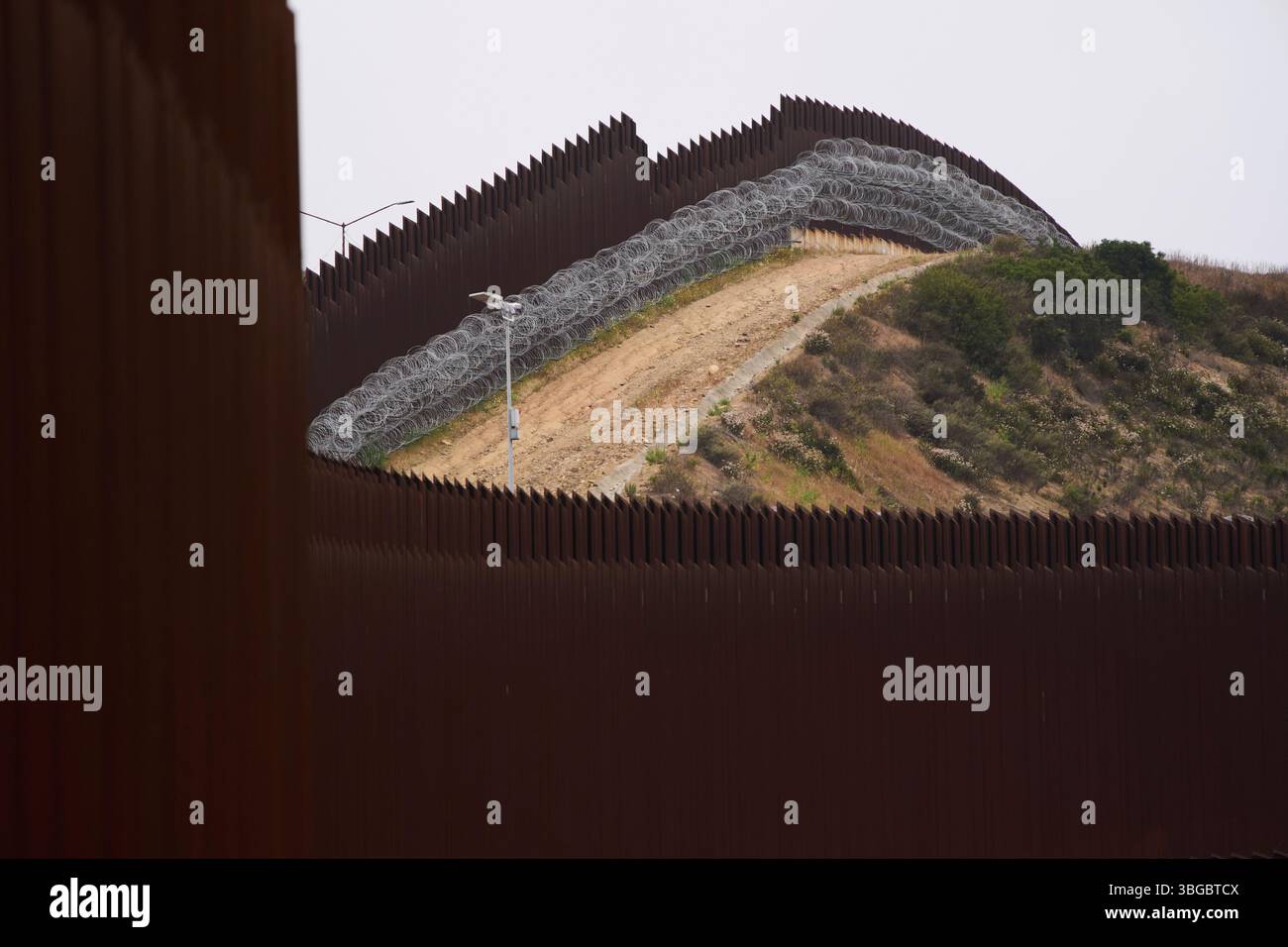 Concertina wire lines the interior of a border wall, one of two ...