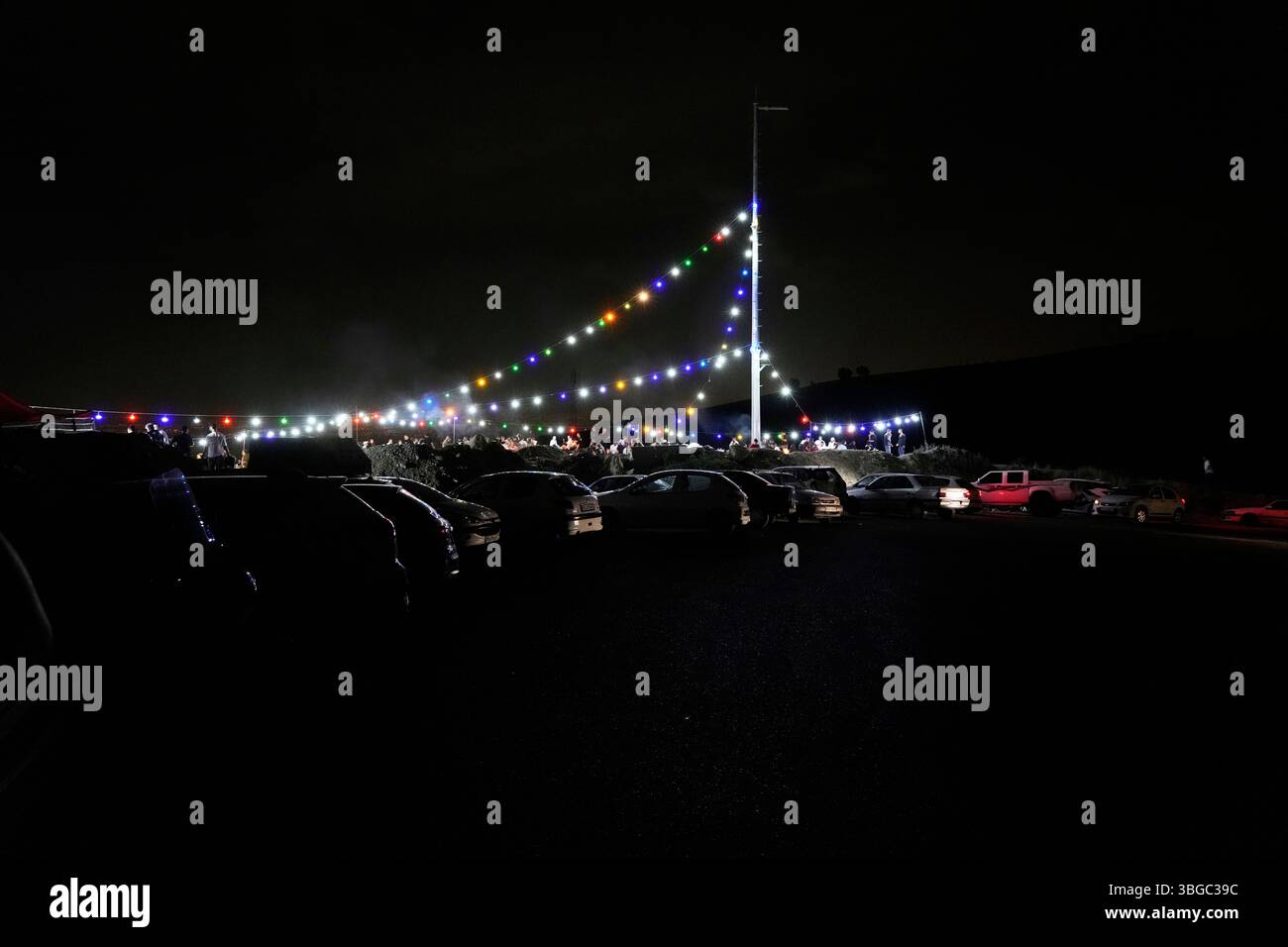 Decorative lights glow beside cars parked along the roadside at the ...