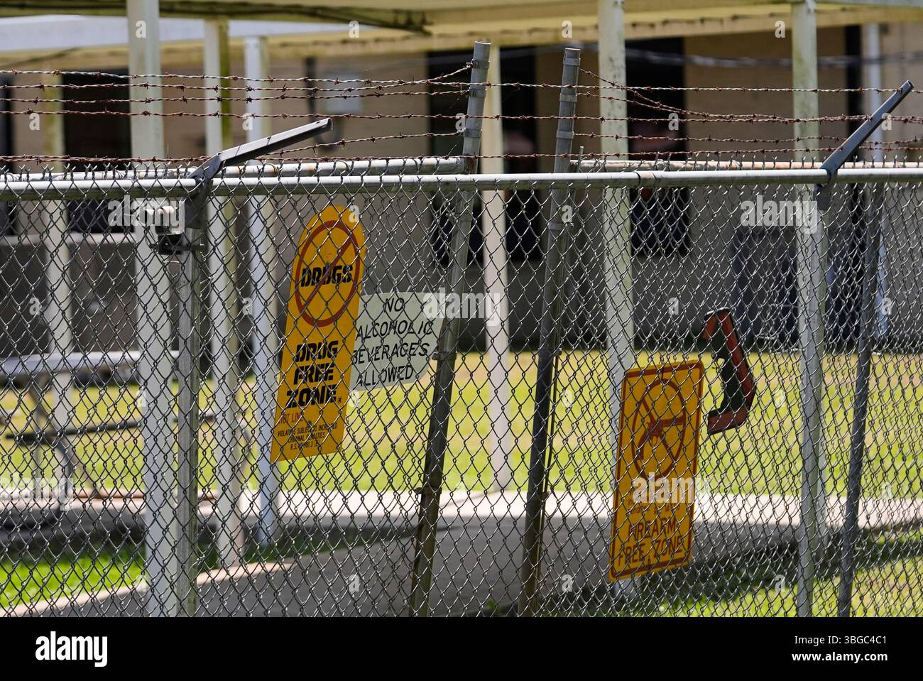 Signs warning of drugs firearms and alcohol are on a fence at a gate ...
