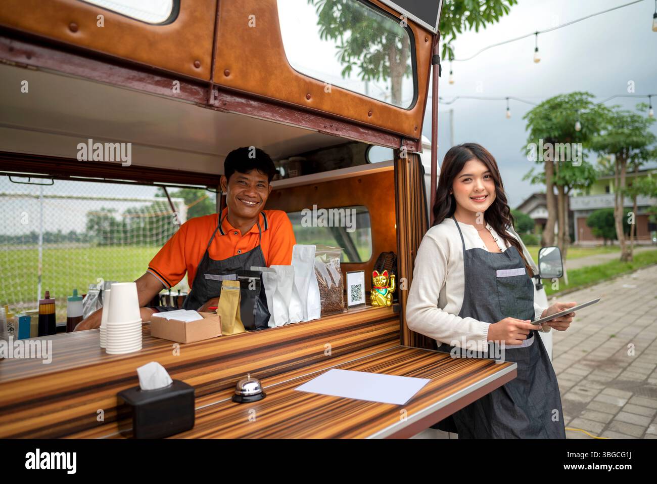 Indonesian southeast asian male with a Chinese female couple barista holding a tablet in their ...