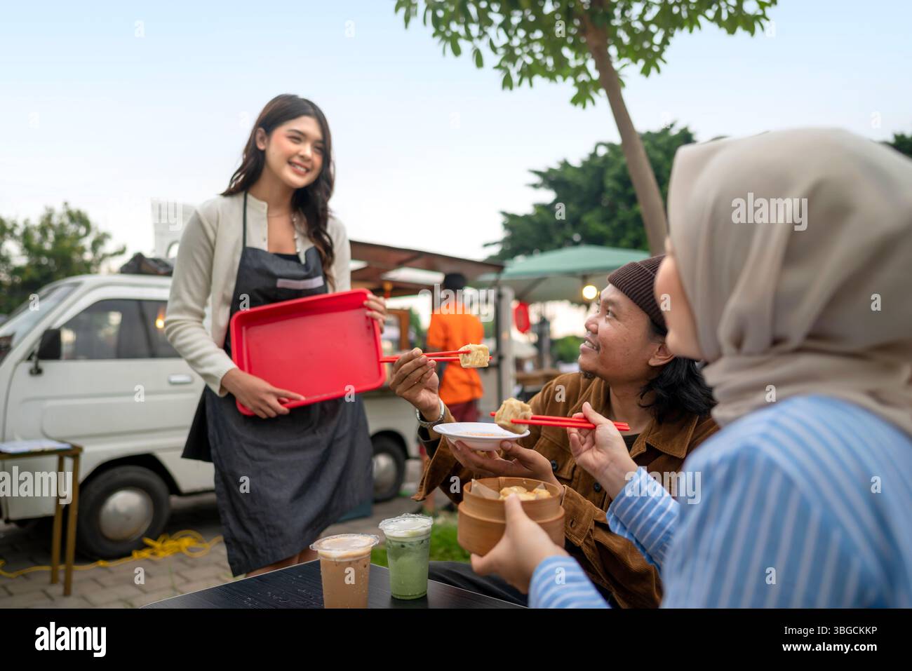 Indonesian southeast chinese asian female waiter serving food and ...
