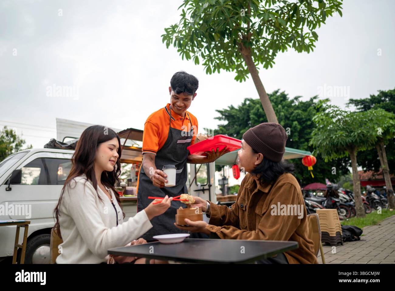 Indonesian southeast asian male waiter serving food order to chinese ...