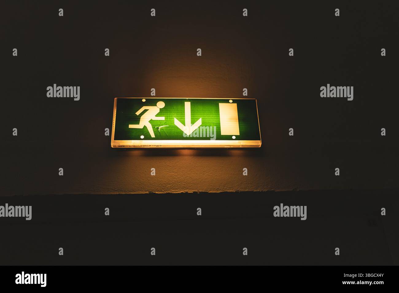 Green emergency exit sign is lit up, showing white running man and ...