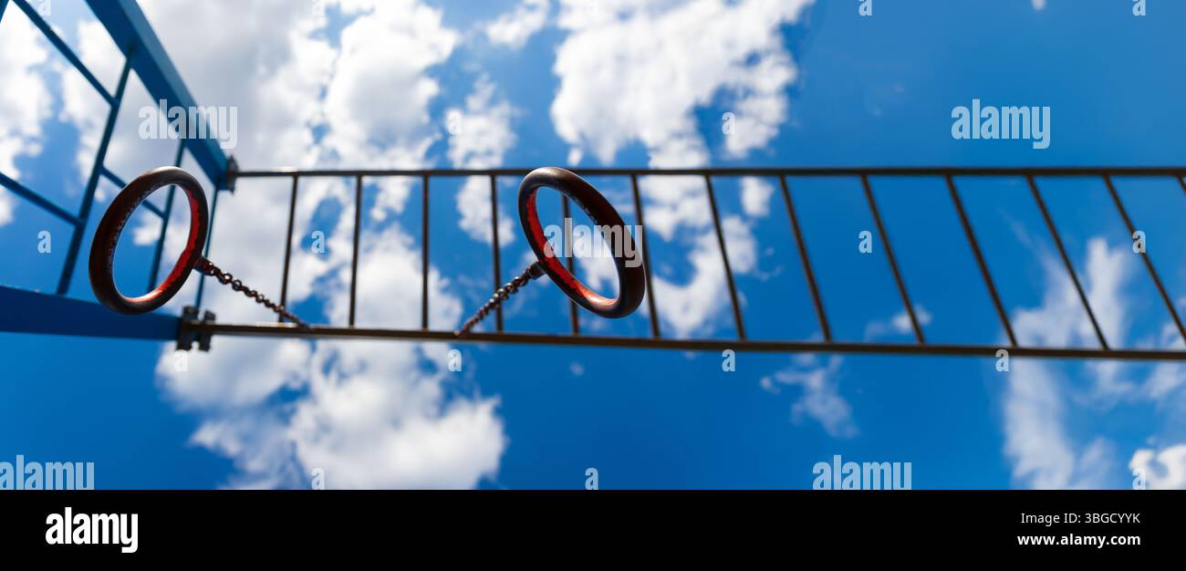 Close-up view of metal gymnastic rings and horizontal ladder bars on a ...