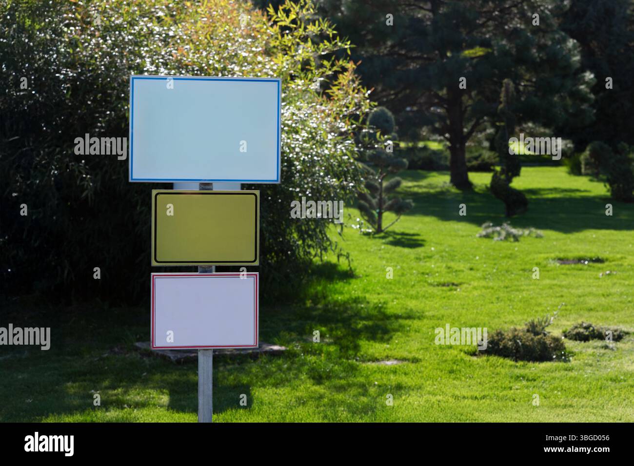 Three empty rectangular signs—blue, yellow, and red bordered—mounted on ...