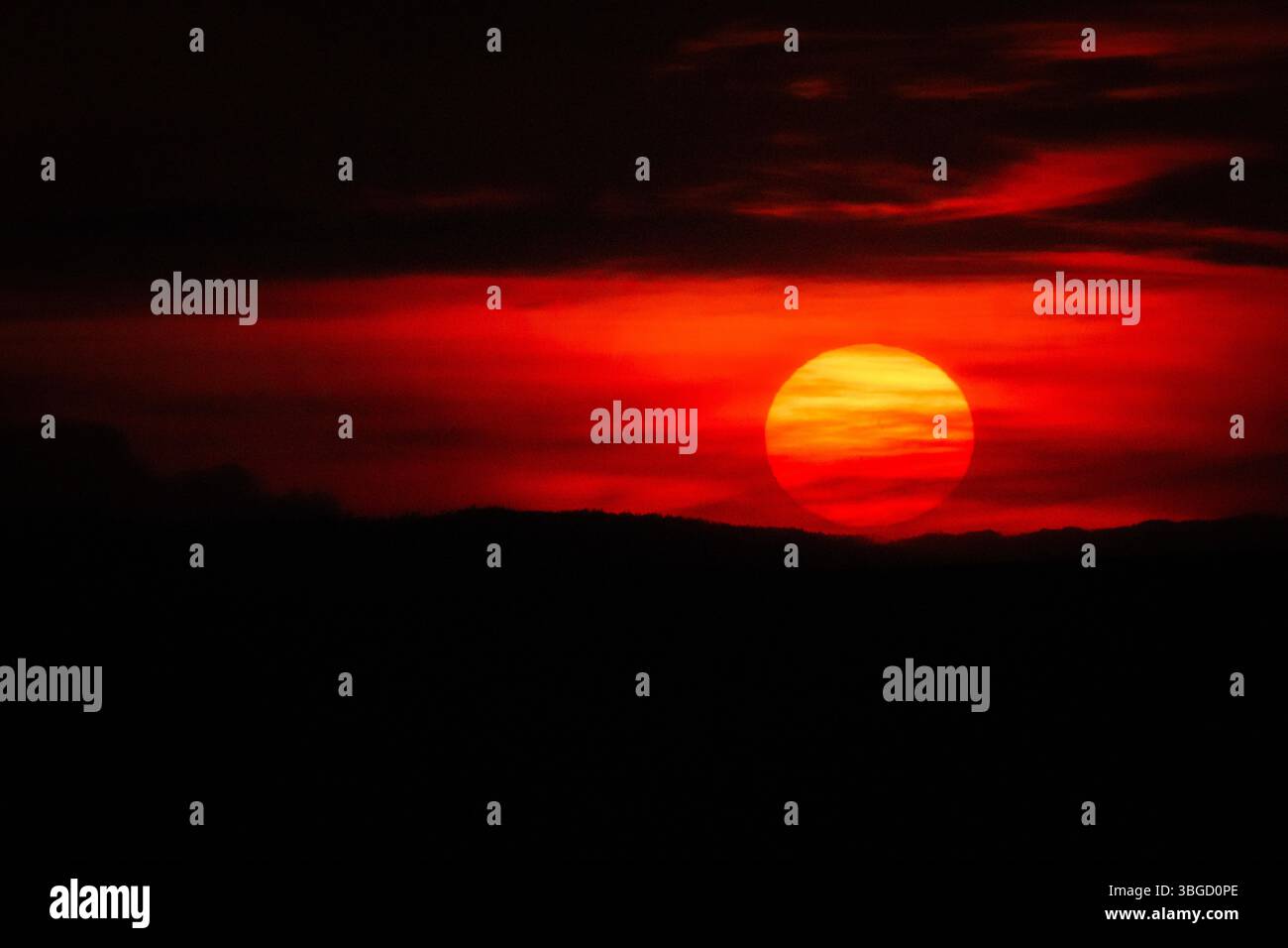 Low on the horizon, the sun sinks into a bed of glowing clouds ...