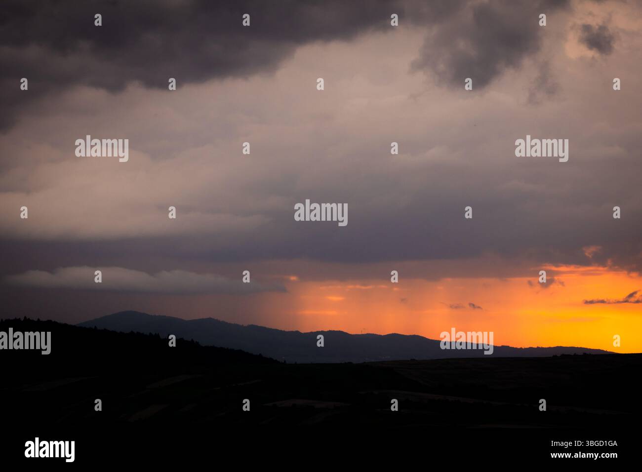 Close-up silhouette of mountain ridge under an indigo dusk sky, with magenta hues bleeding ...