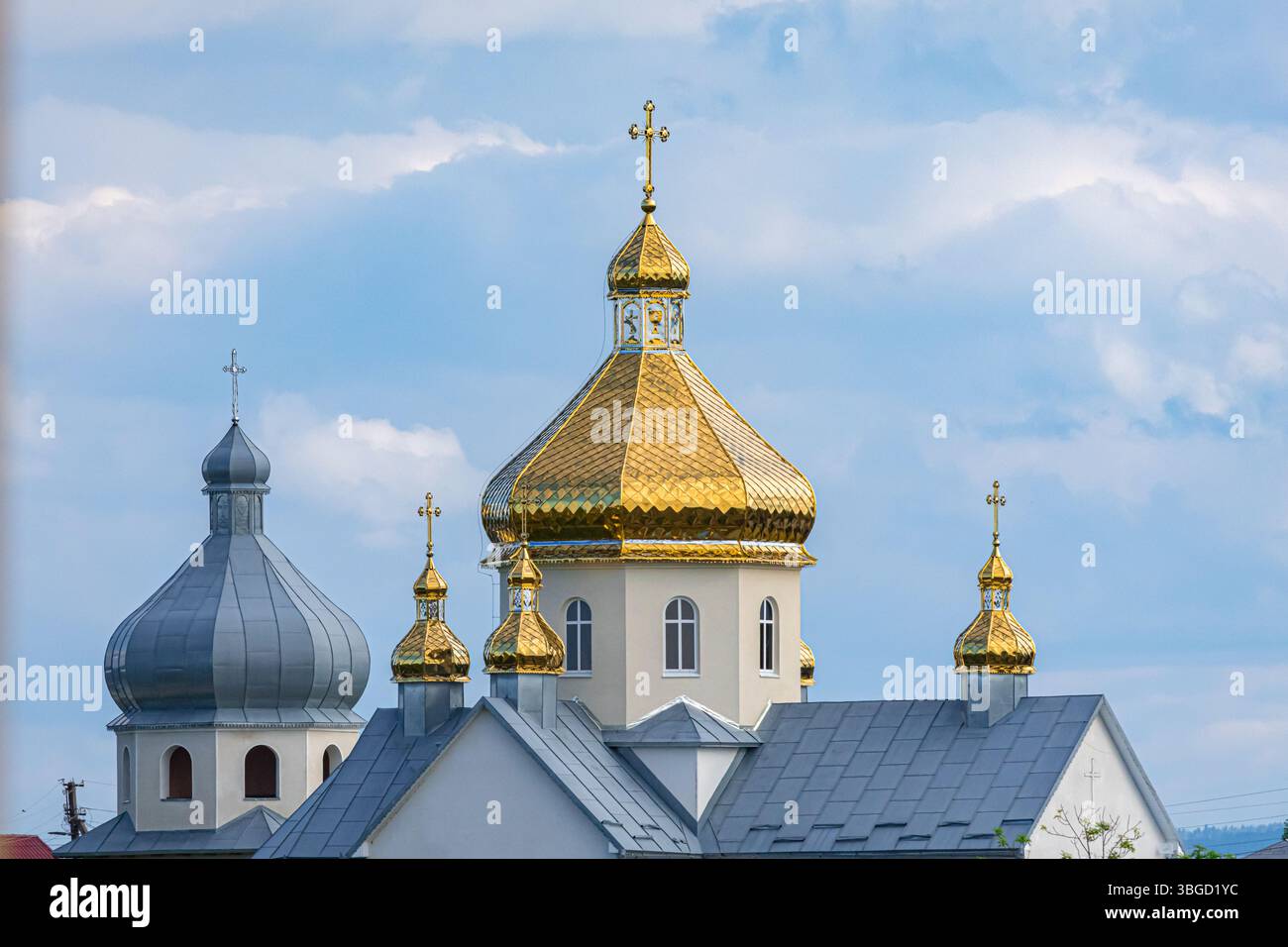 Golden domes of a Ukrainian Orthodox church shine against a cloudy blue ...