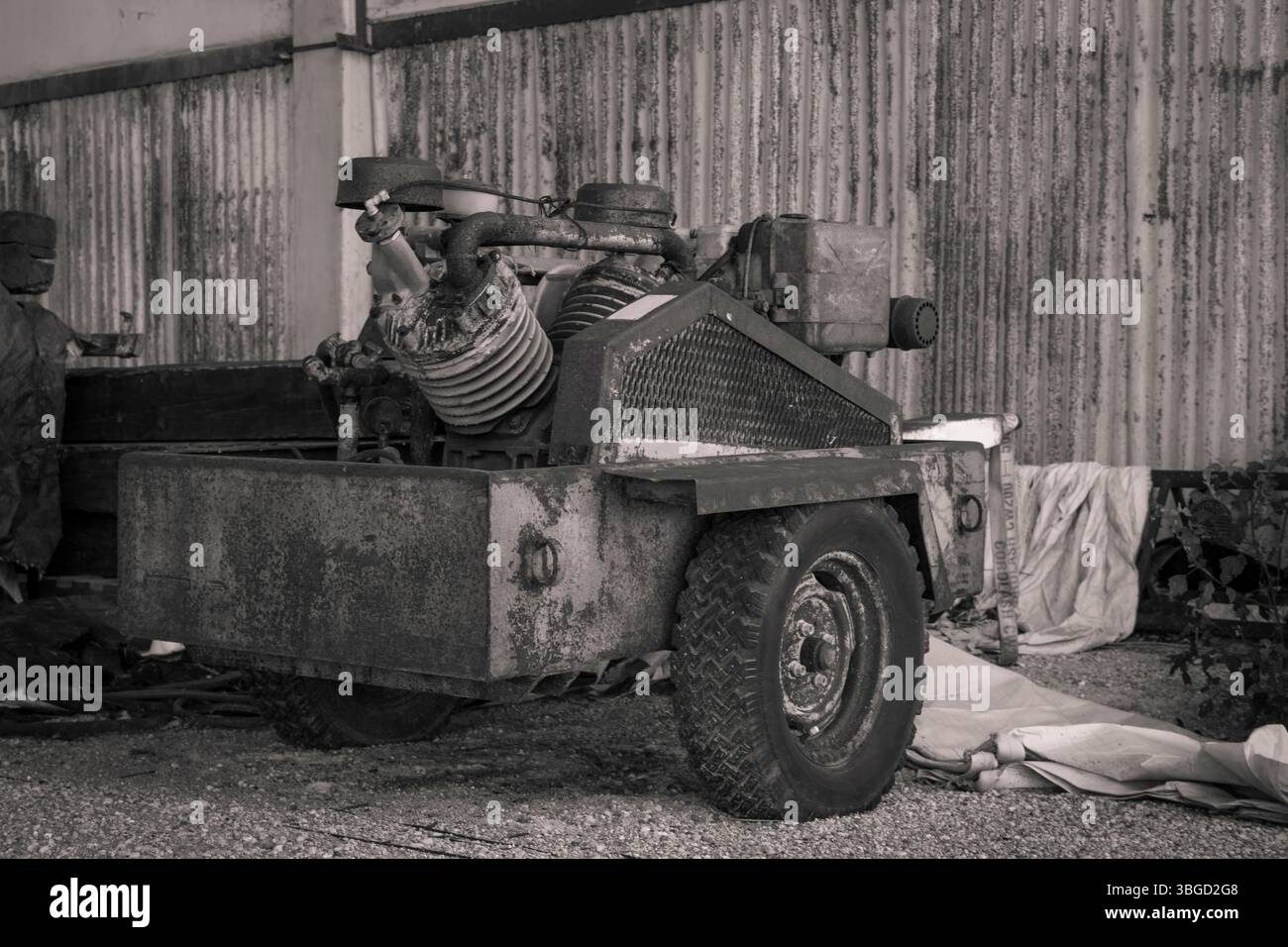 Old rusty air compressor with a trailer parked near a corrugated metal ...