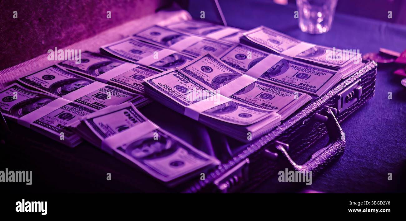 Open briefcase overflowing with stacks of hundred dollar bills bathed ...