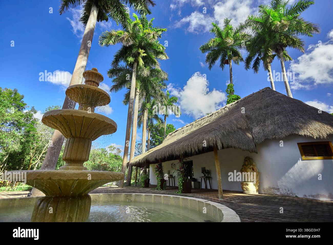 Stone fountain splashing water near a traditional mayan hut with ...